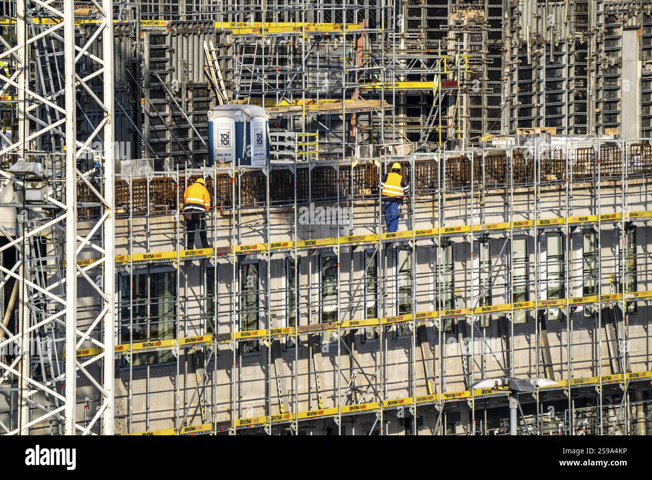 Large construction site, scaffolded new building, factory and office building, workers on the ...