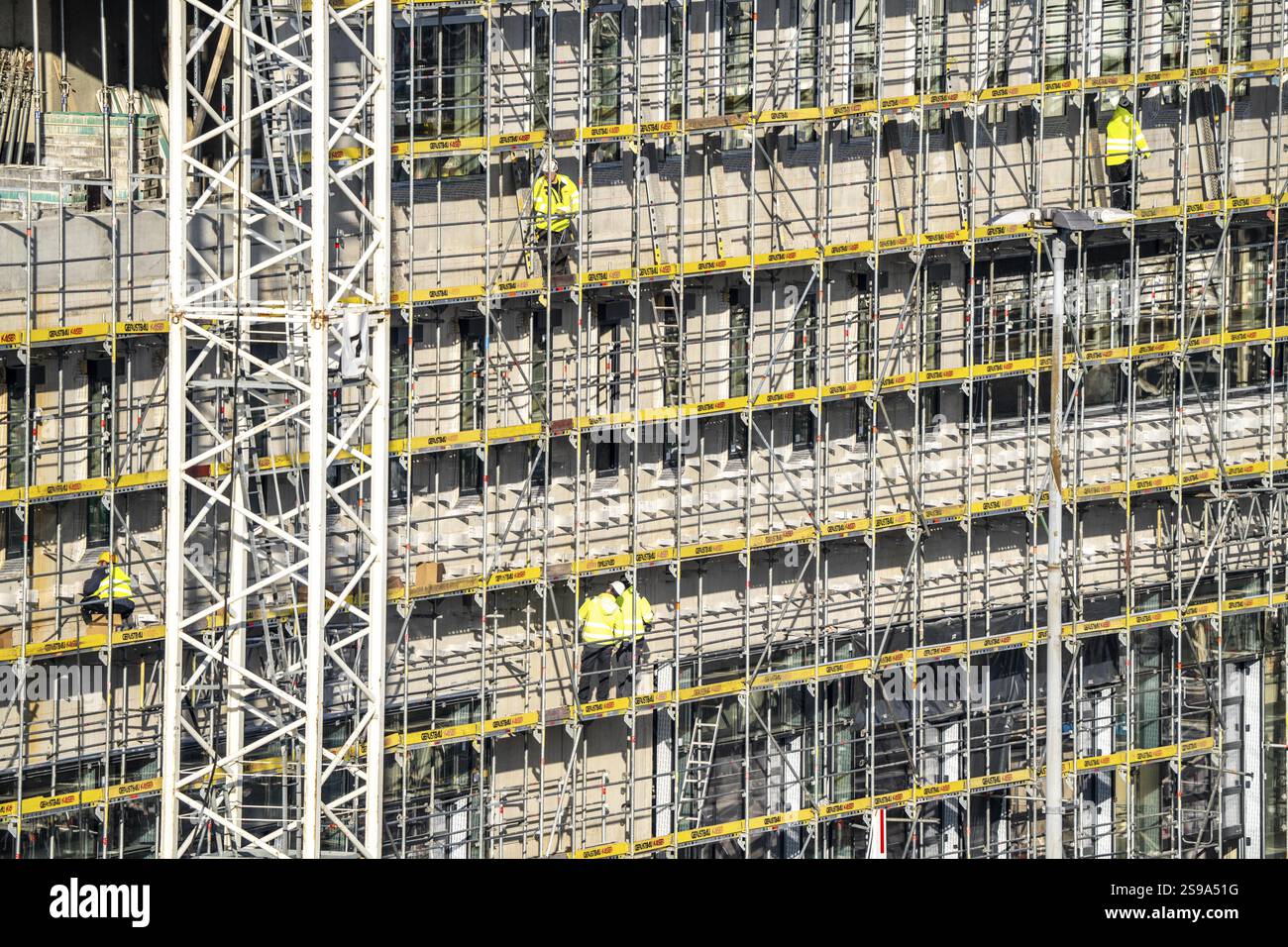Large construction site, scaffolded new building, factory and office building, workers on the ...