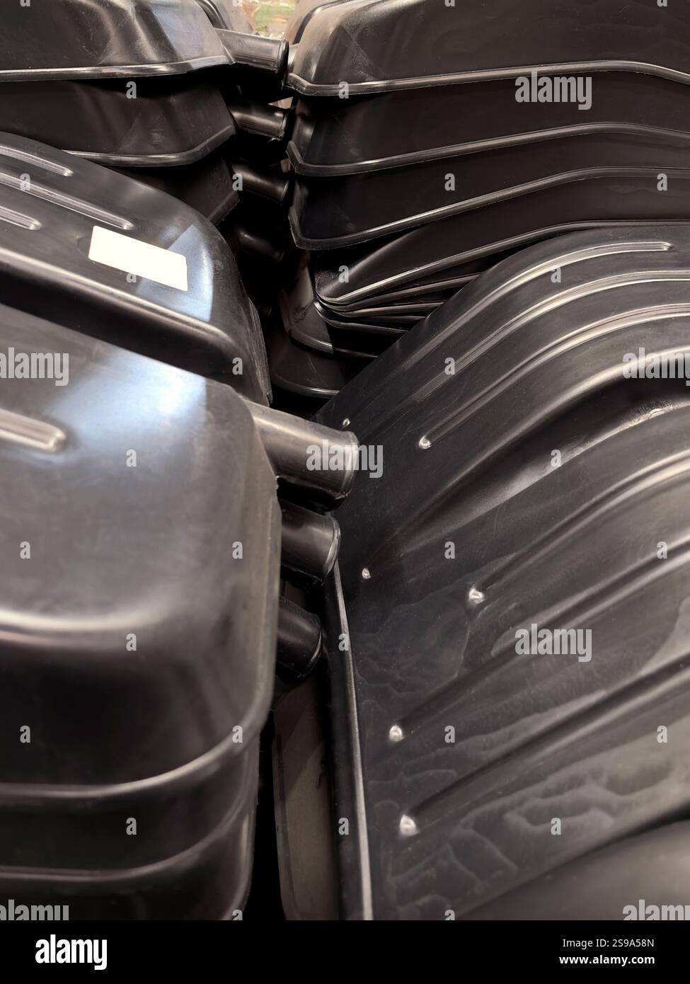 Black containers are neatly stacked in layers, showcasing their smooth ...