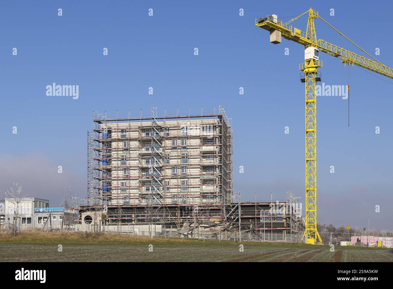 Incomplete building with yellow construction crane in clear sky ...