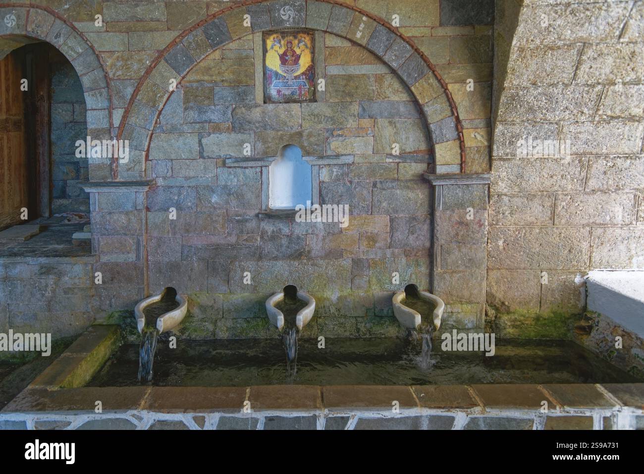 Ancient stone fountain with three water sources, marble basin and mural ...