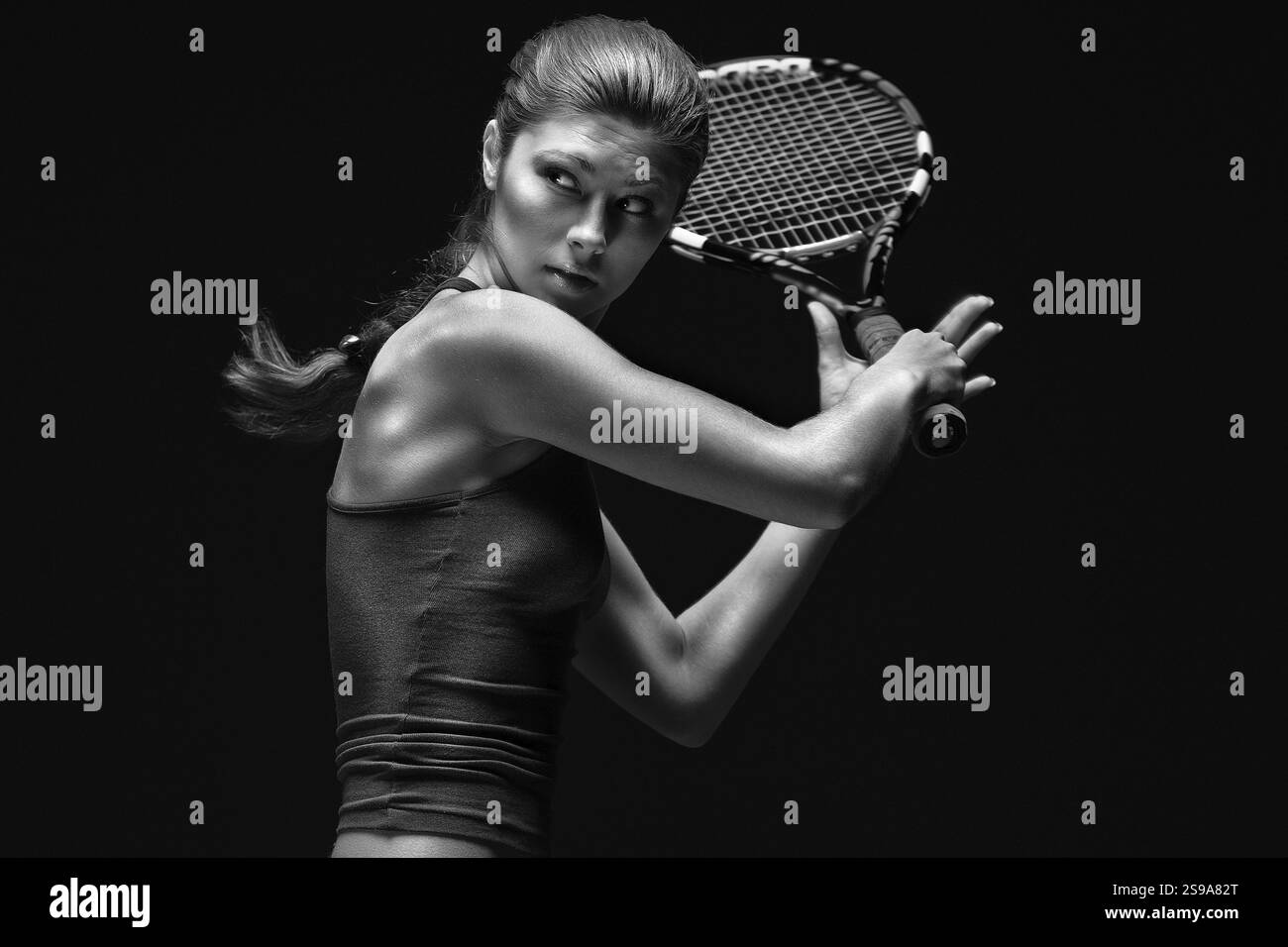 Tennis player holding racket behind her head, in front of black ...