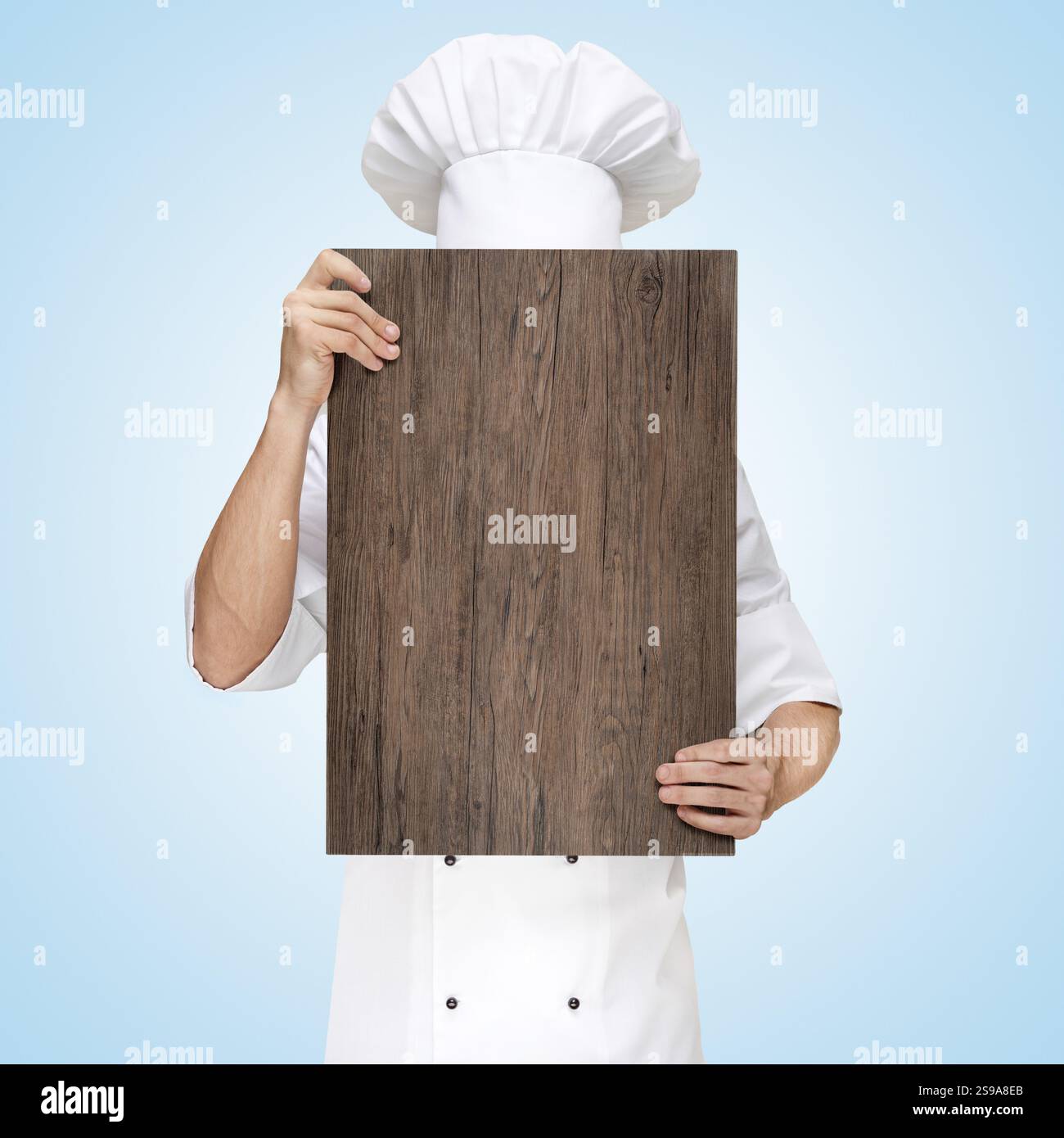 Restaurant chef hides behind a wooden chopping board for a business ...