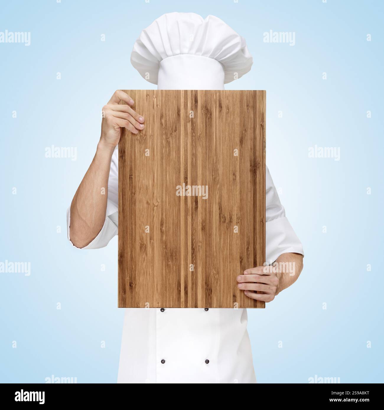 Restaurant chef hides behind a wooden chopping board for a business ...