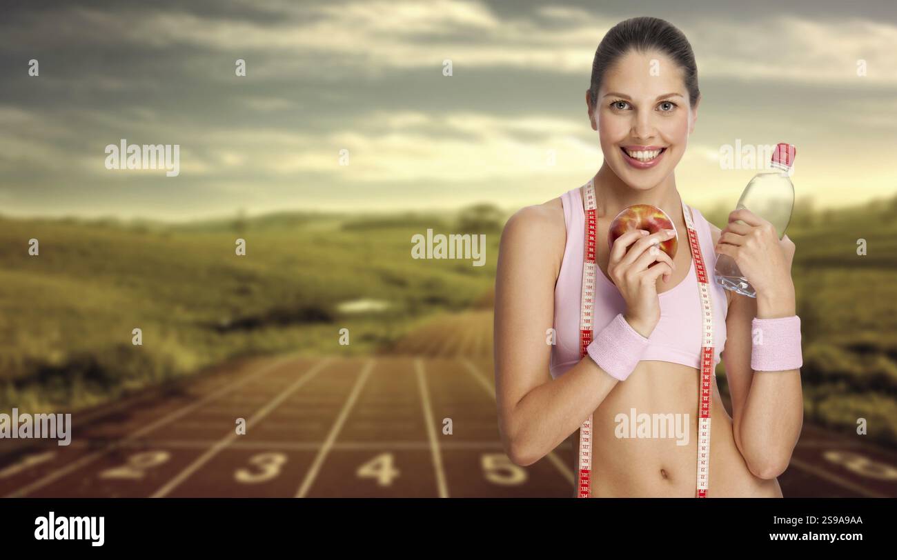 A young athletic woman with water and an apple in her hand on a running track Stock Photo - Alamy