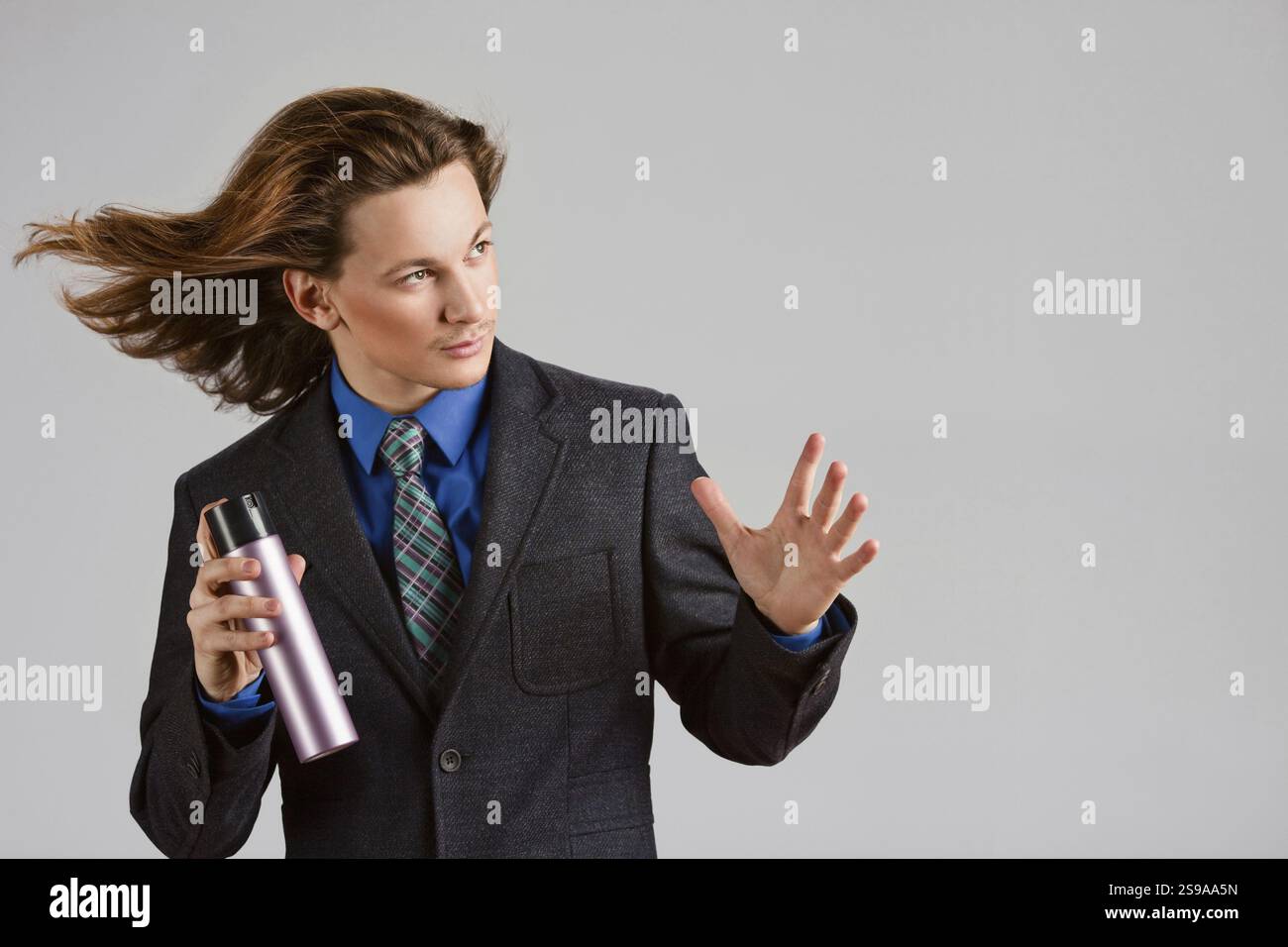 Portrait of a handsome long-haired man in a suit holding a bottle of ...