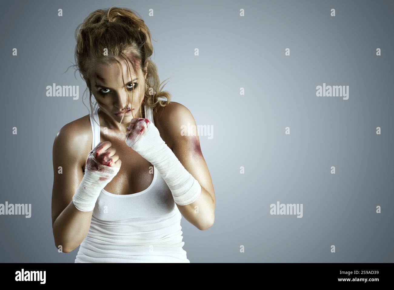 Aggressive female fighter with bruises, wearing a bloody bandage around ...