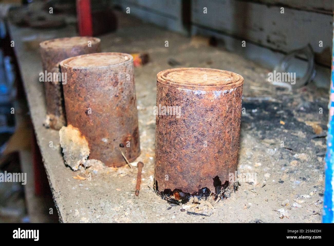 Three rusty cans are sitting on a table. The cans are old and worn, and ...