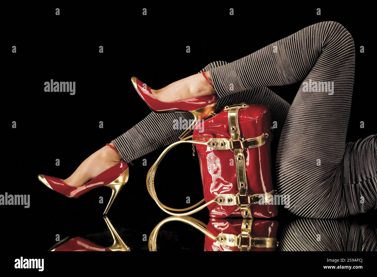 Long legs of a female model with red high-heeled shoes and a purse ...