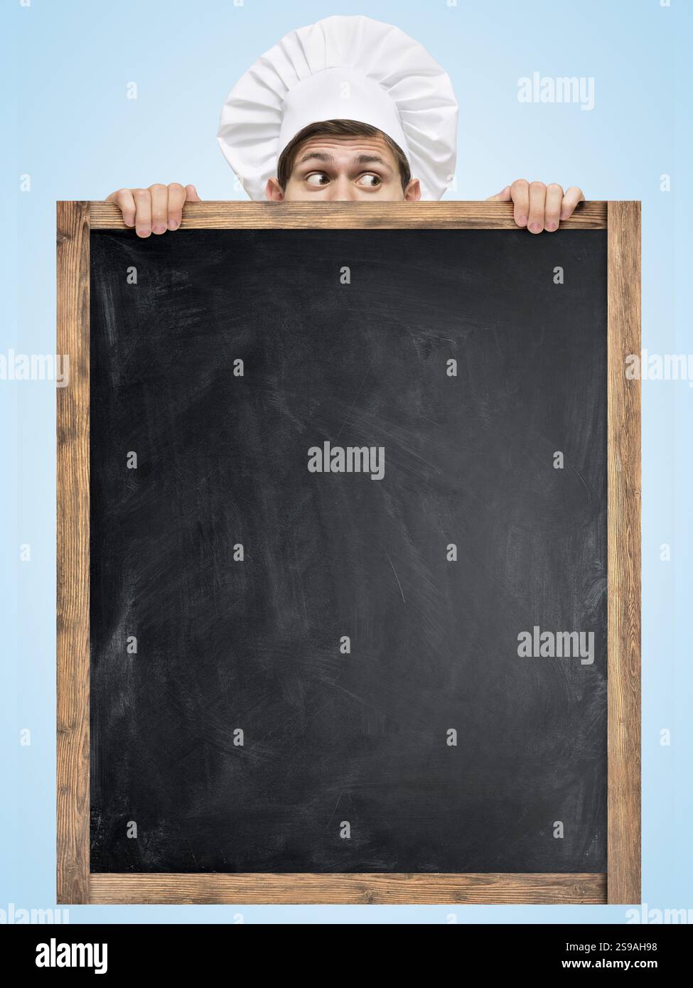 Restaurant chef hides behind a large blank chalkboard for a business ...