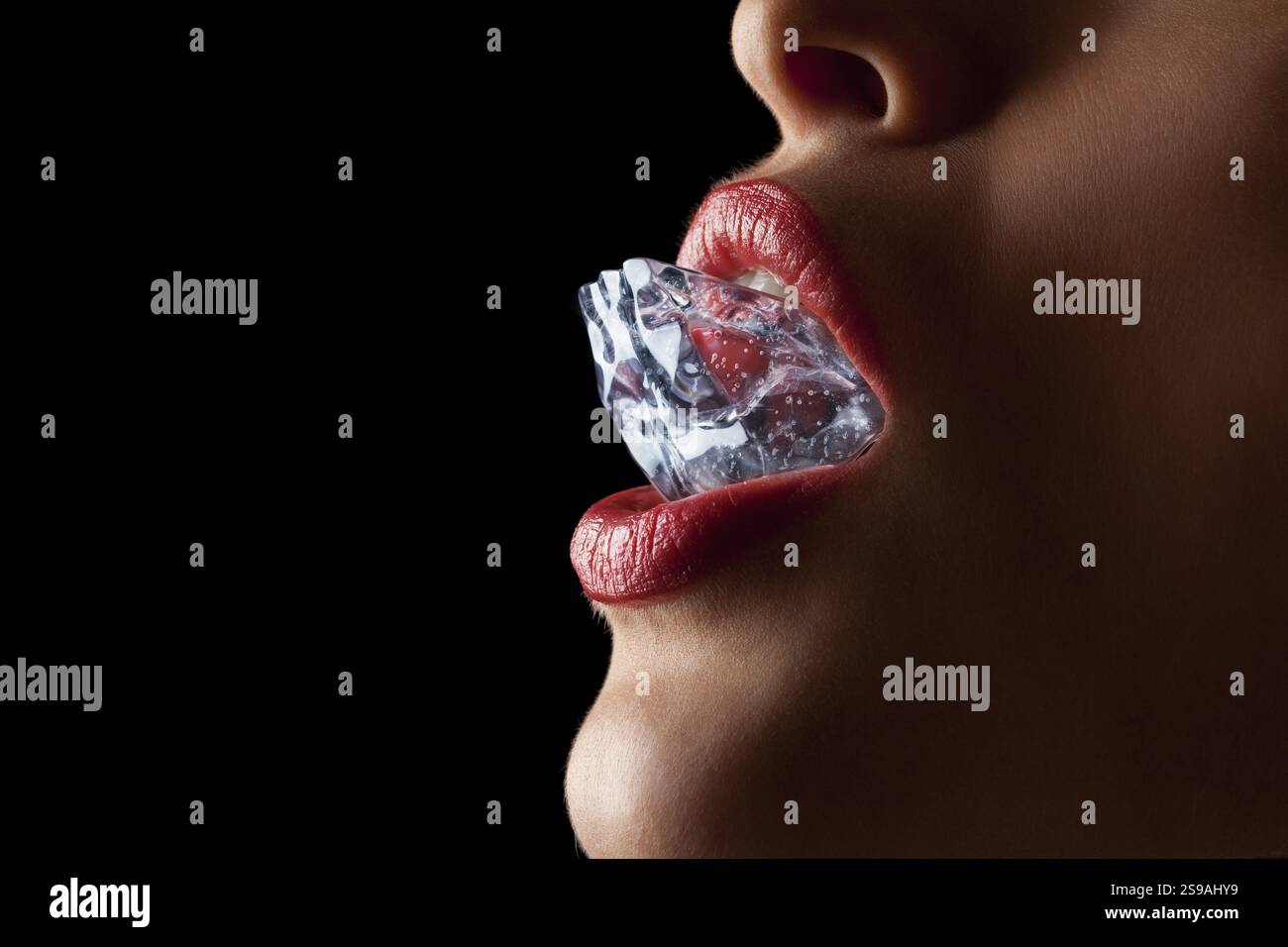 Ice cubes in a woman's mouth against a black background Stock Photo - Alamy