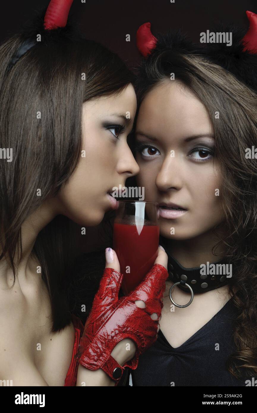 Two women in outlandish carnival costumes. Devil figure Stock Photo - Alamy