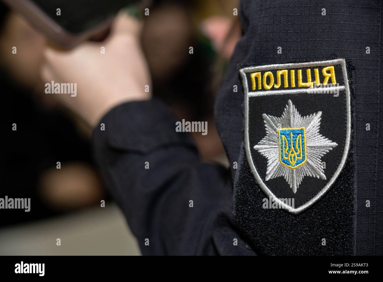 A police officer wearing a dark uniform stands with a badge displayed ...