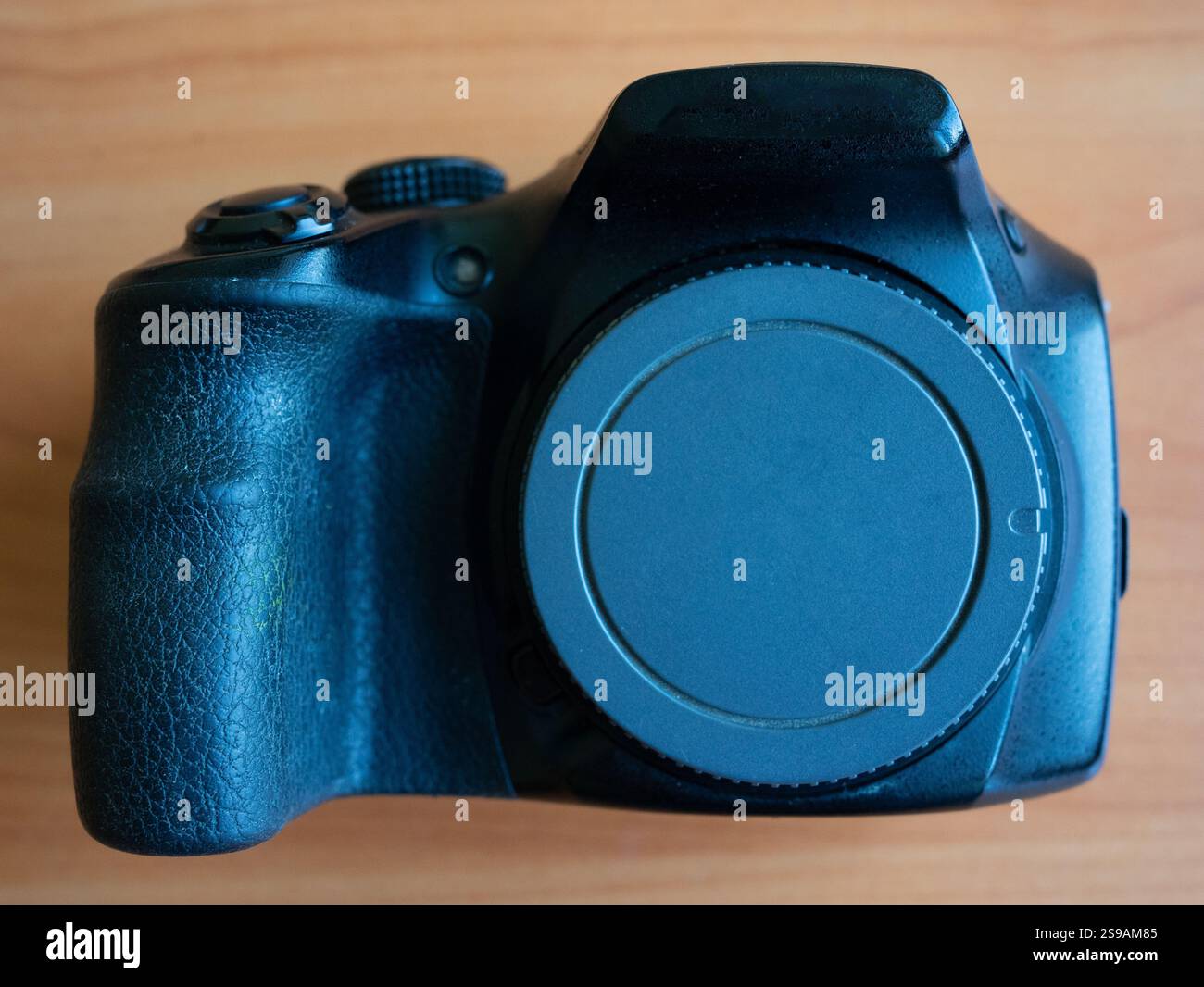 A black camera is placed on a wooden surface, showcasing the top view ...