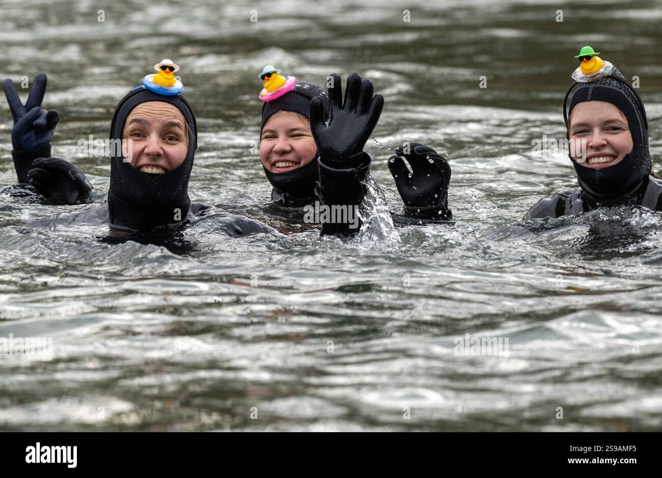 25 January 2025, Bavaria, Neuburg a.d.Donau: Three women in wetsuits ...