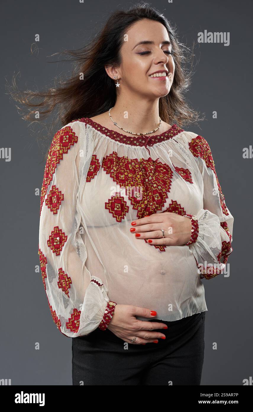 Pregnant woman wearing a traditional embroidered blouse with red ...
