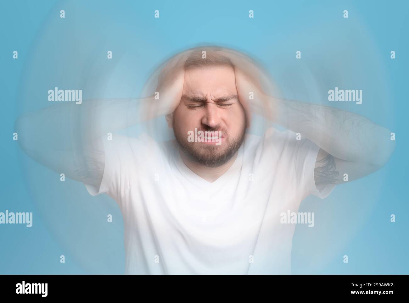 Man suffering from headache and dizziness on light blue background ...