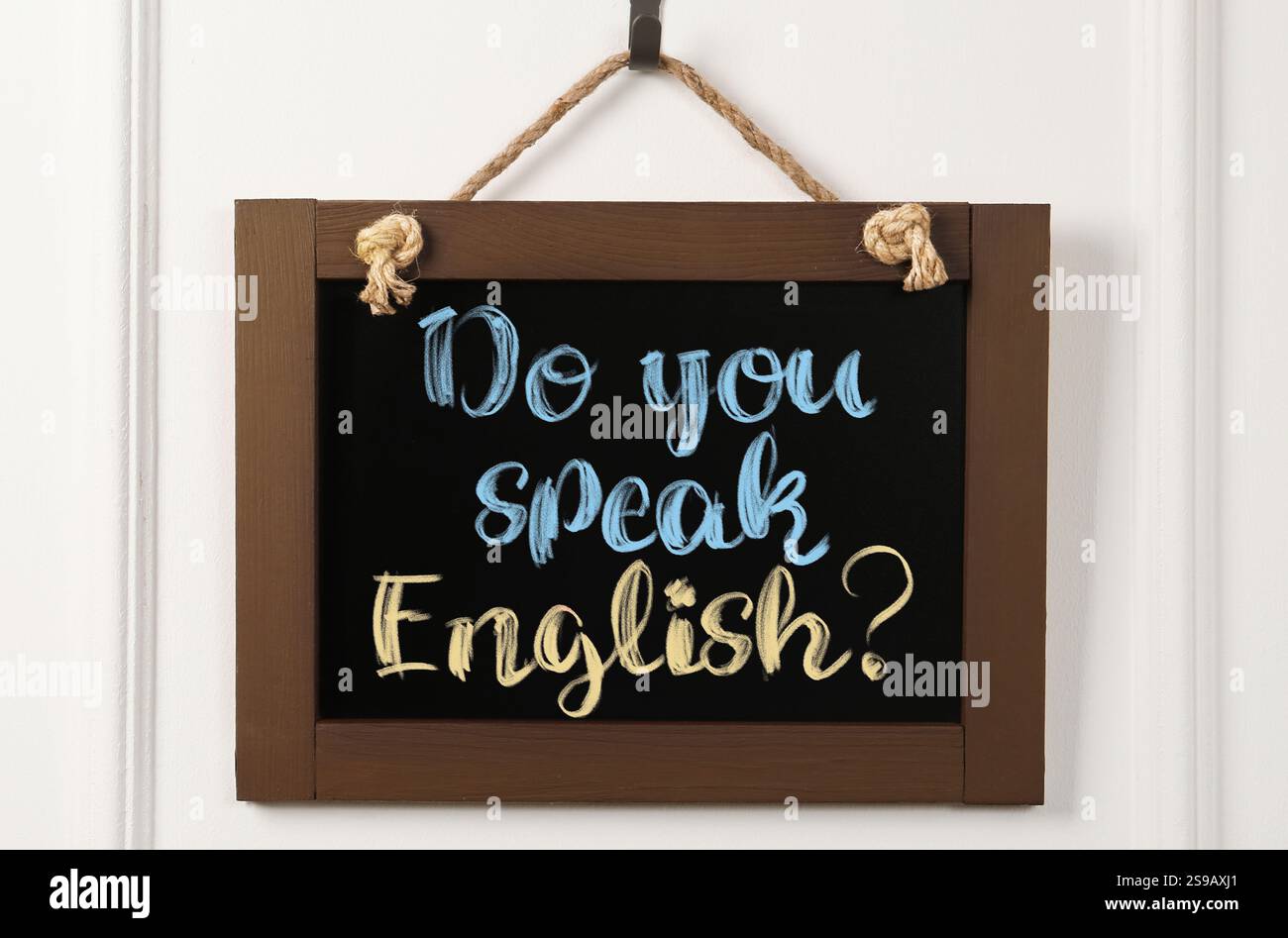 Small black chalkboard with text Do You Speak English? on white wall ...