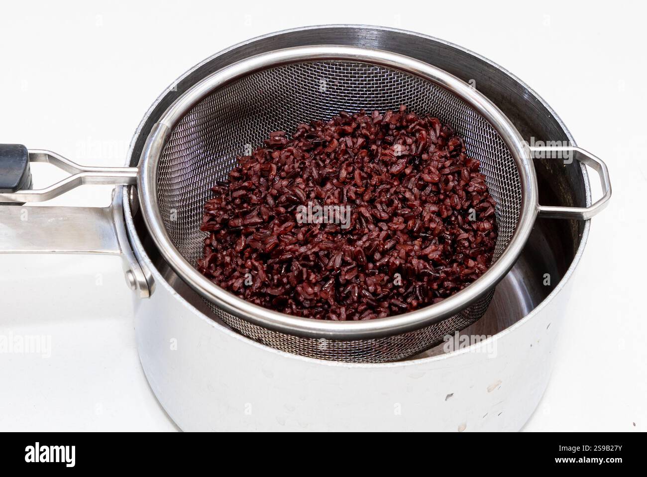 Cooked whole grain brown rice inside metal strainer in kitchen Stock ...