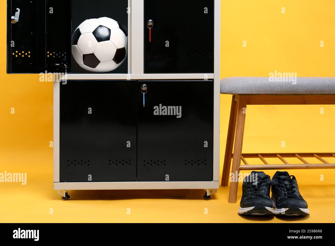 Open locker with soccer ball, bench and sneakers on orange background ...