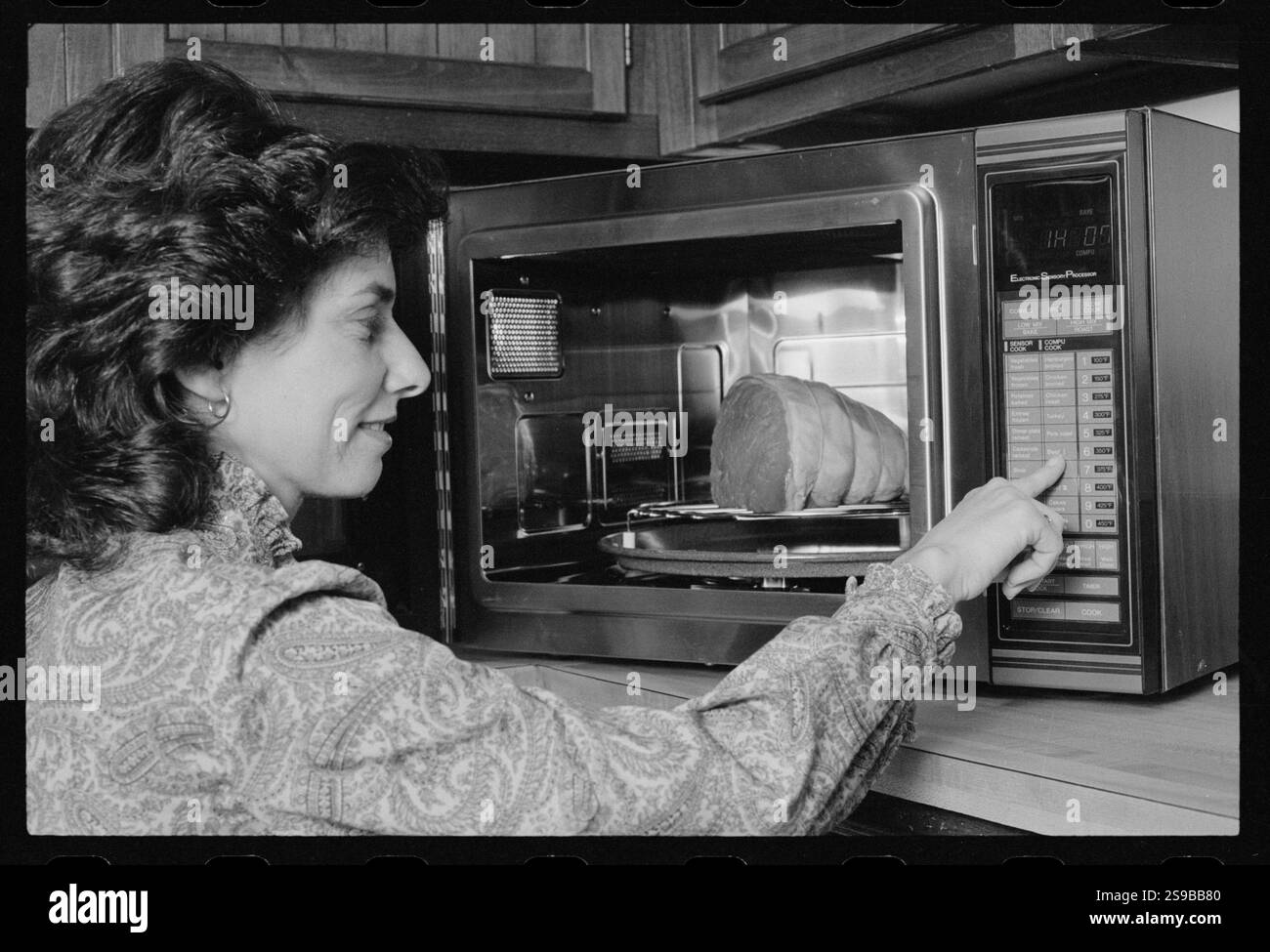 Unidentified woman prepares meat for cooking in a microwave oven by ...