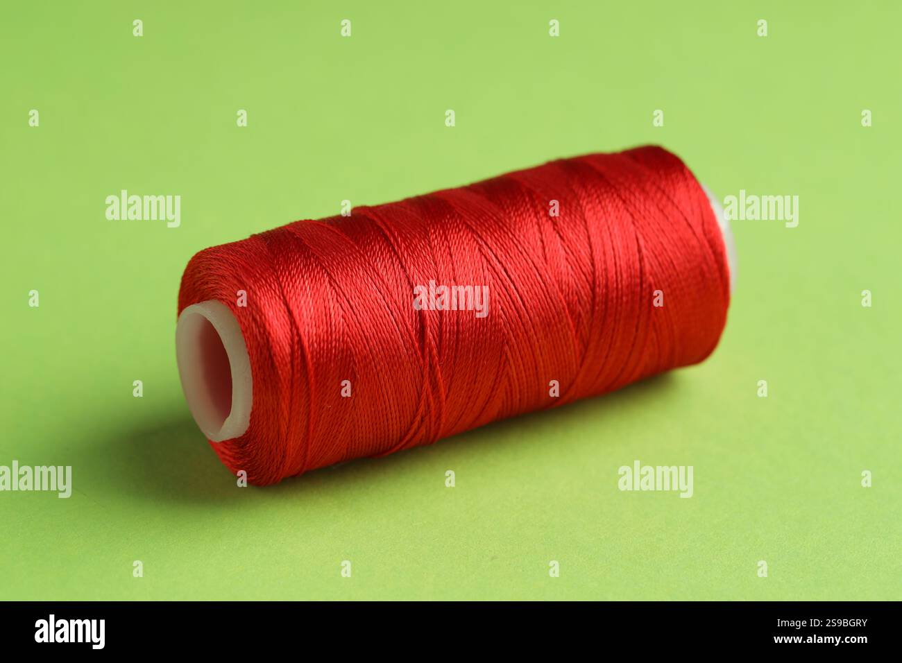 Spool of red sewing thread on green background, closeup Stock Photo - Alamy