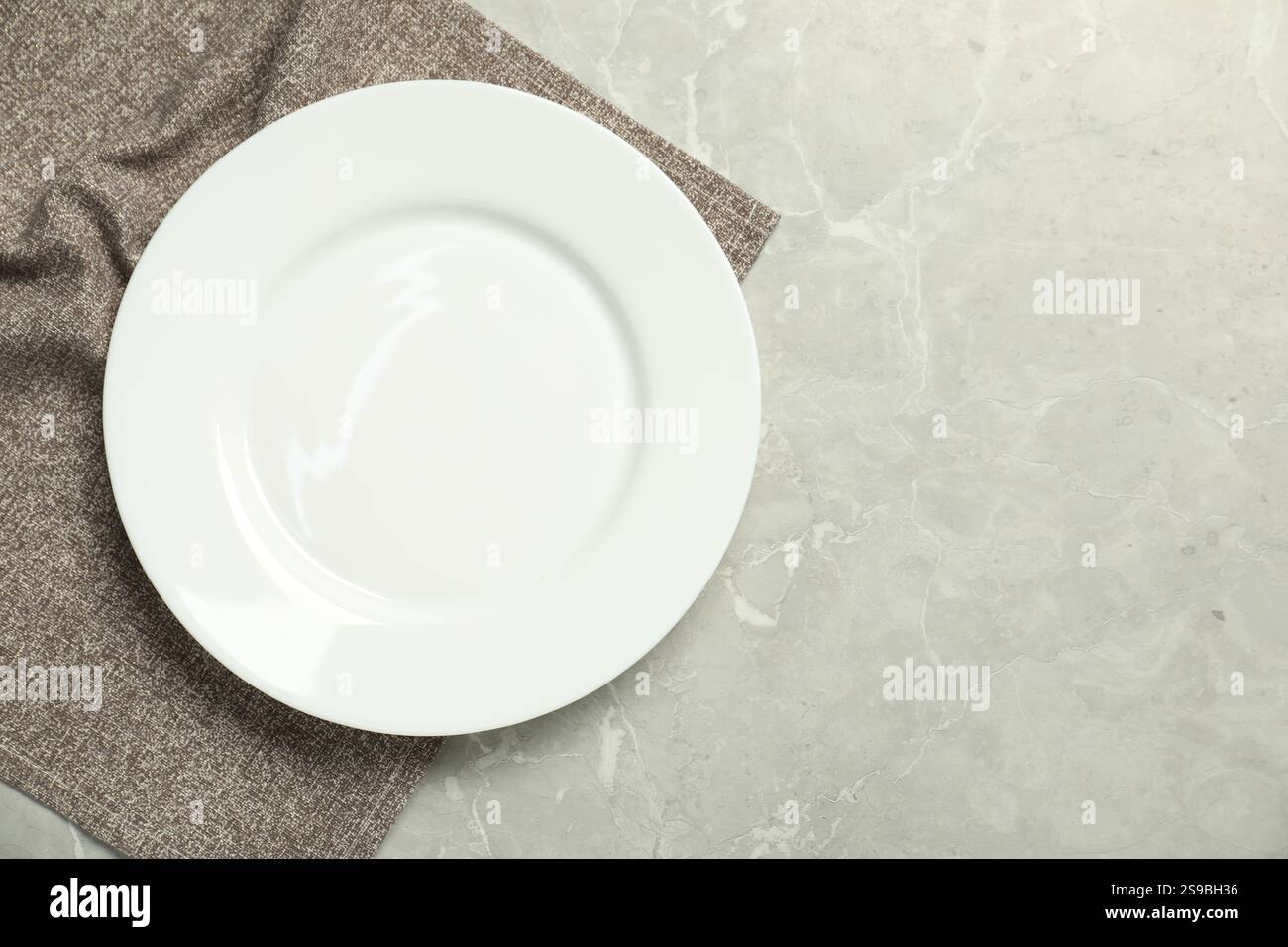 Napkin and empty plate on grey marble table, top view. Space for text ...