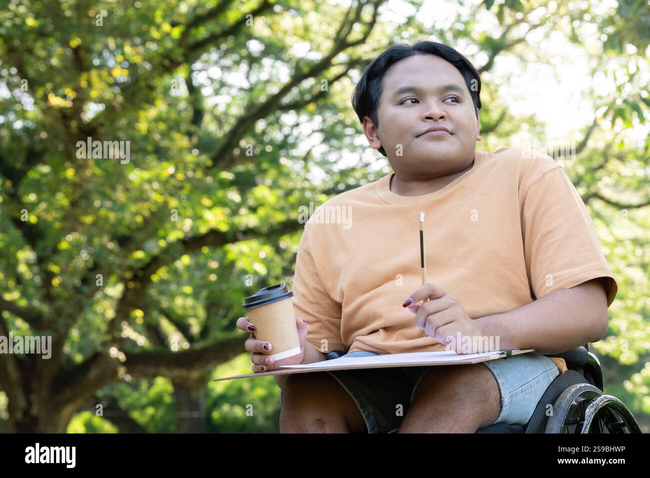 Disabled artist in wheelchair enjoying coffee while sketching in a lush ...