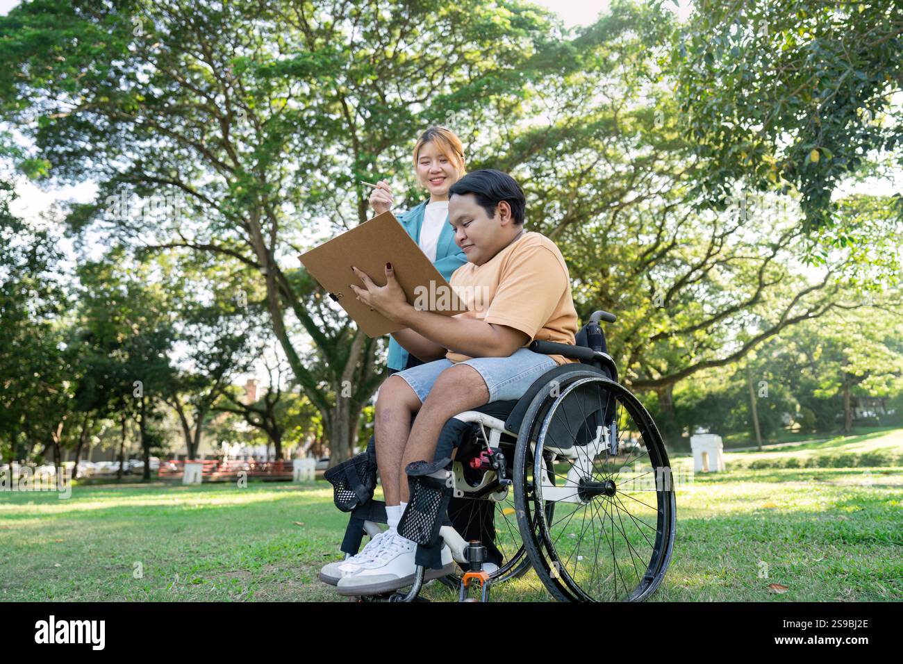 Disabled artist creating artwork with encouragement from instructor in ...