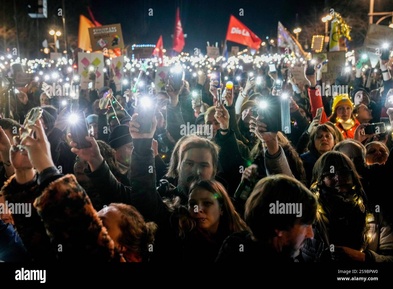 People hold up their cell phones as they protest the far-right ...