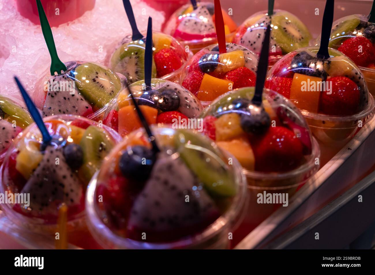 Several glasses of fruit salad with small forks wait in the window of a ...
