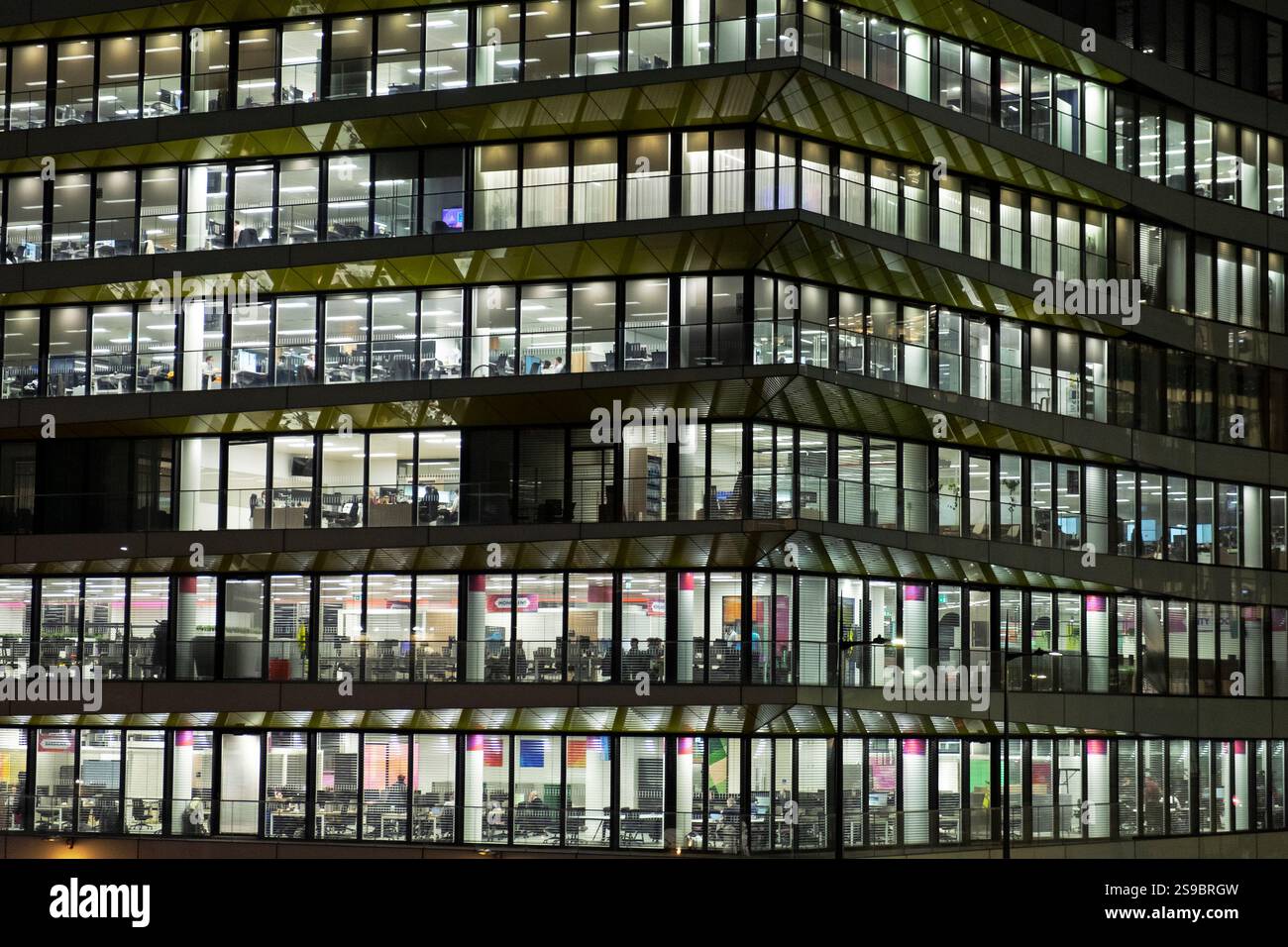 People workers working inside office buildings offices windows lit up ...