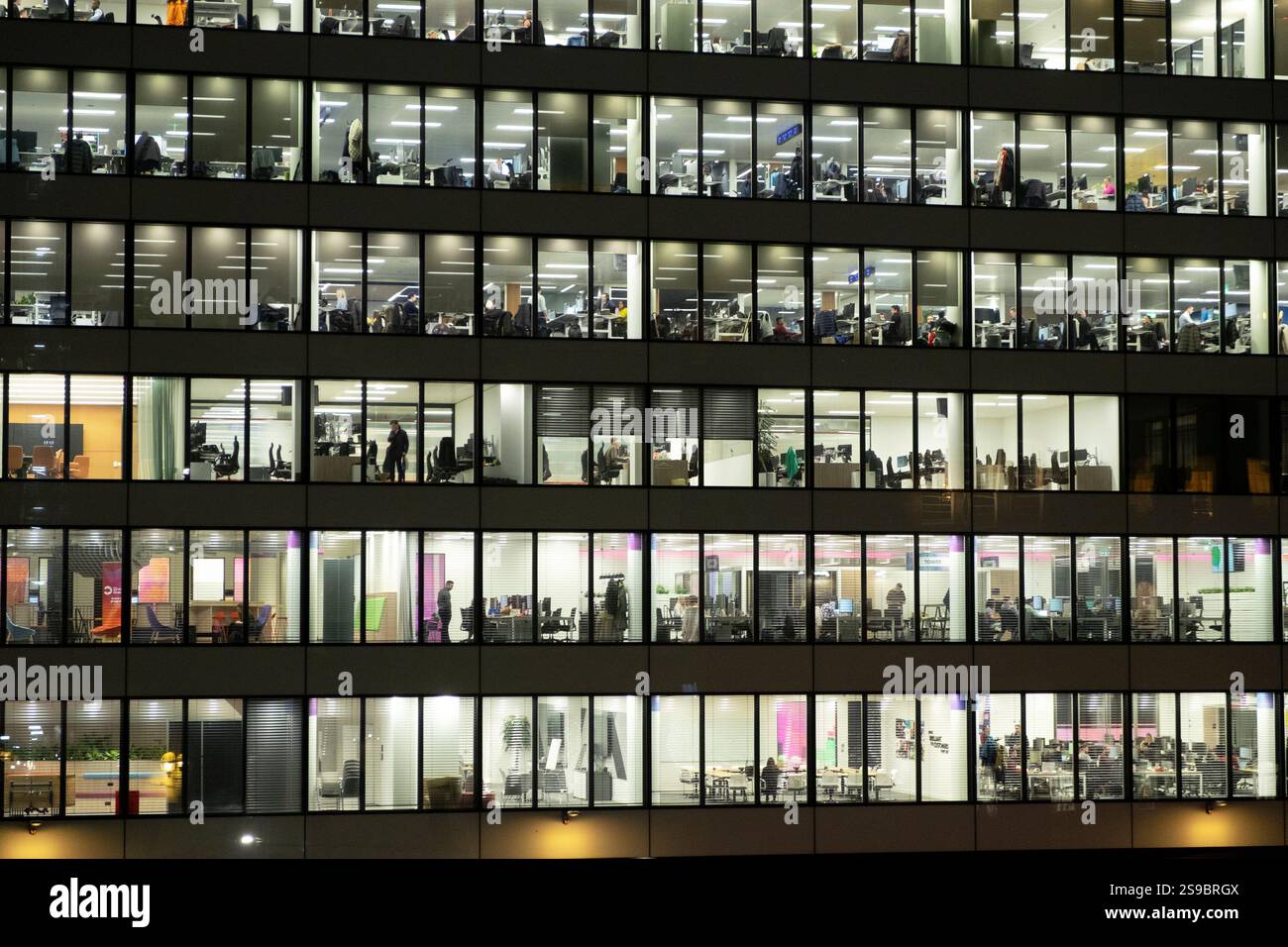 Modern glass exterior view low rise lights in office buildings workers ...