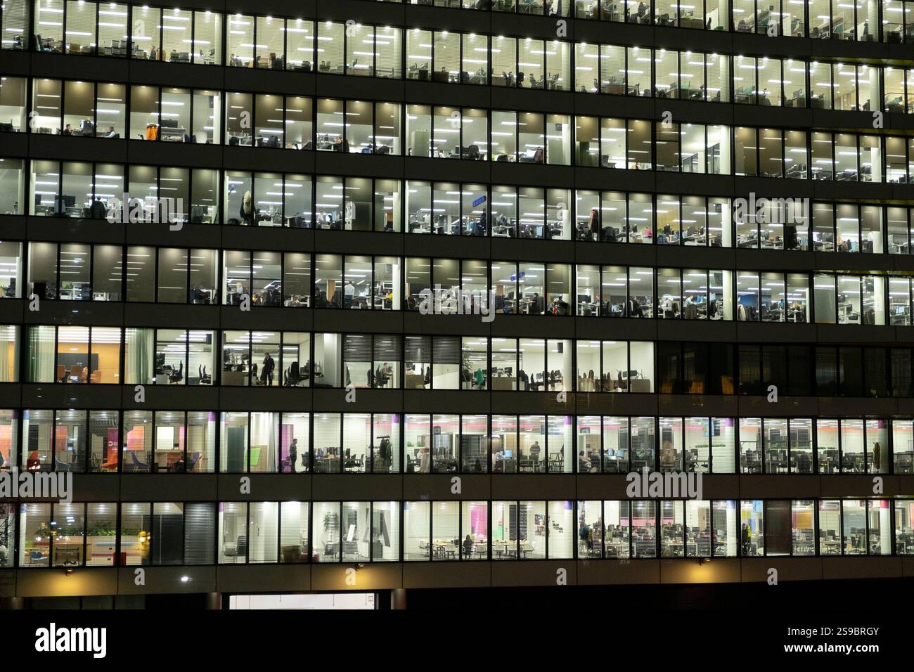 People workers working inside office buildings offices windows lit up ...