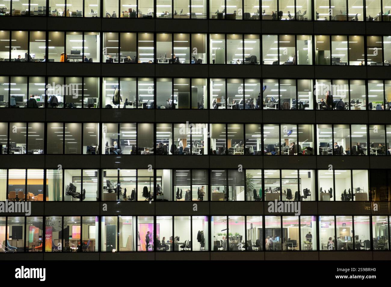 Modern glass exterior view low rise lights in office buildings workers ...