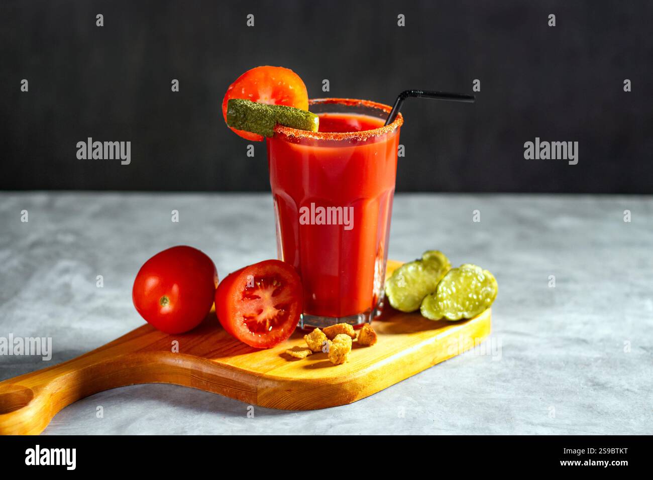 Bloody Mary cocktail in glass served with tomatoes and pickles on grey ...