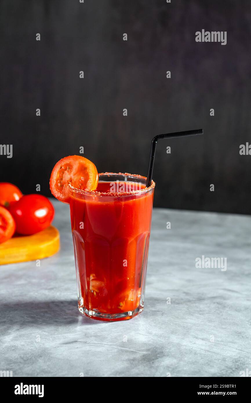 Vegetable shaken cocktail in glass on dark grey background. Red tomato ...