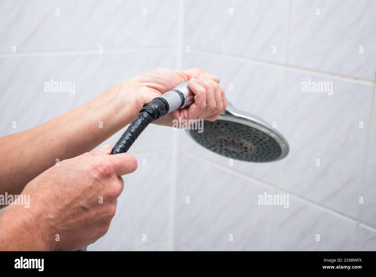 Woman changing broken shower hose in bathroom. Female plumber hands ...
