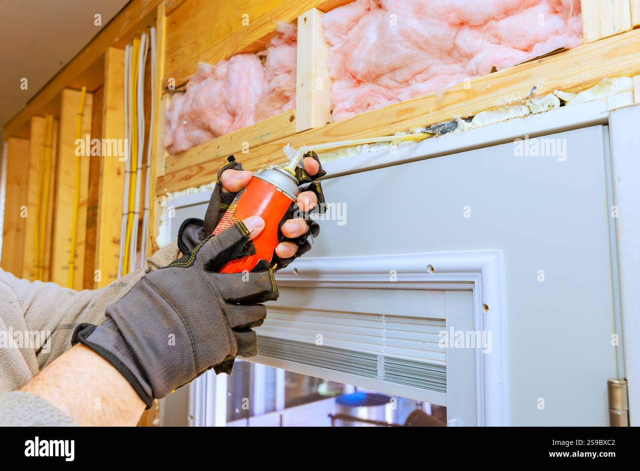 Person applies weatherproofing foam spray around door frame during home ...