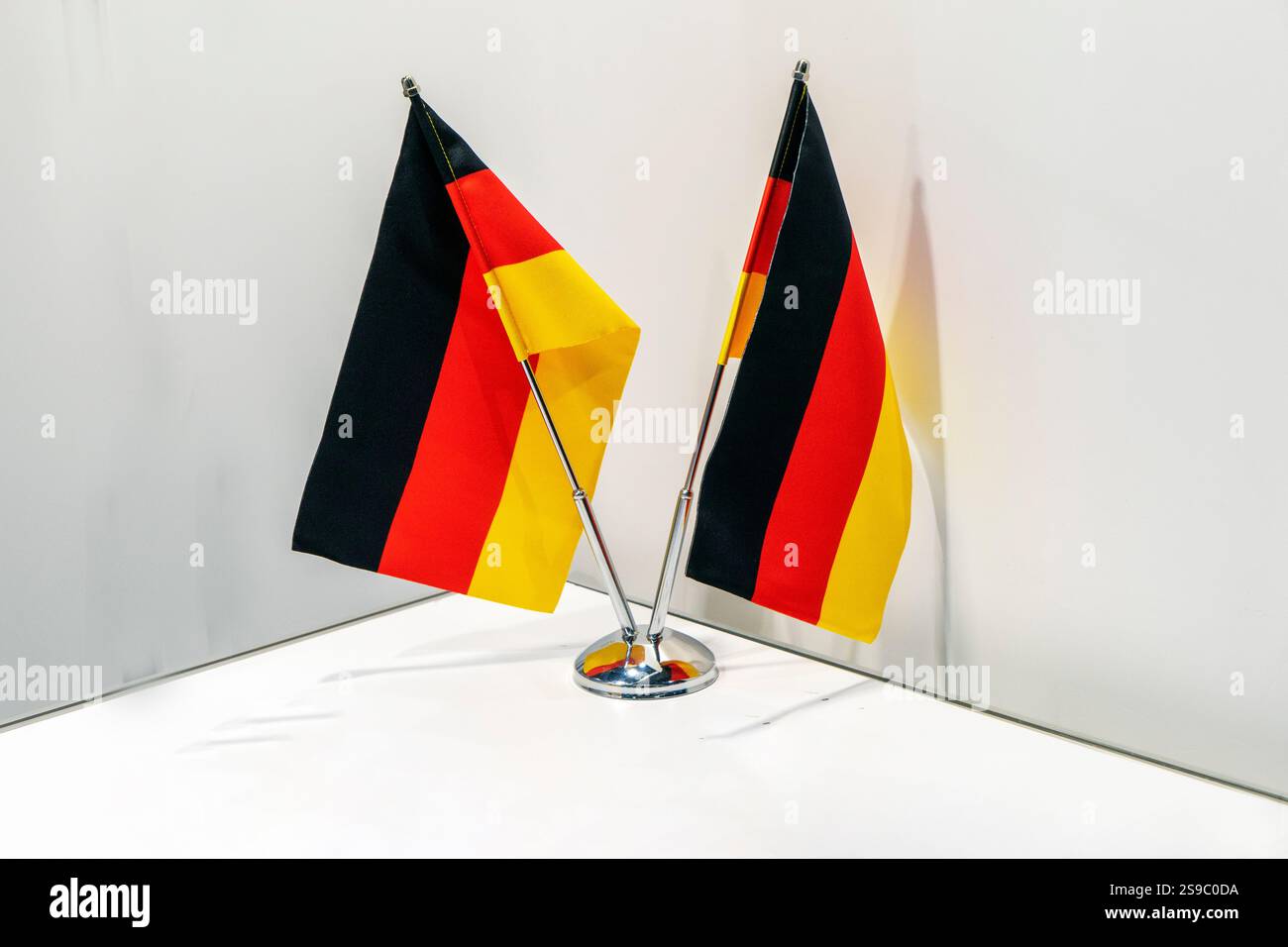 Two small national German flags on a small table on a white background ...