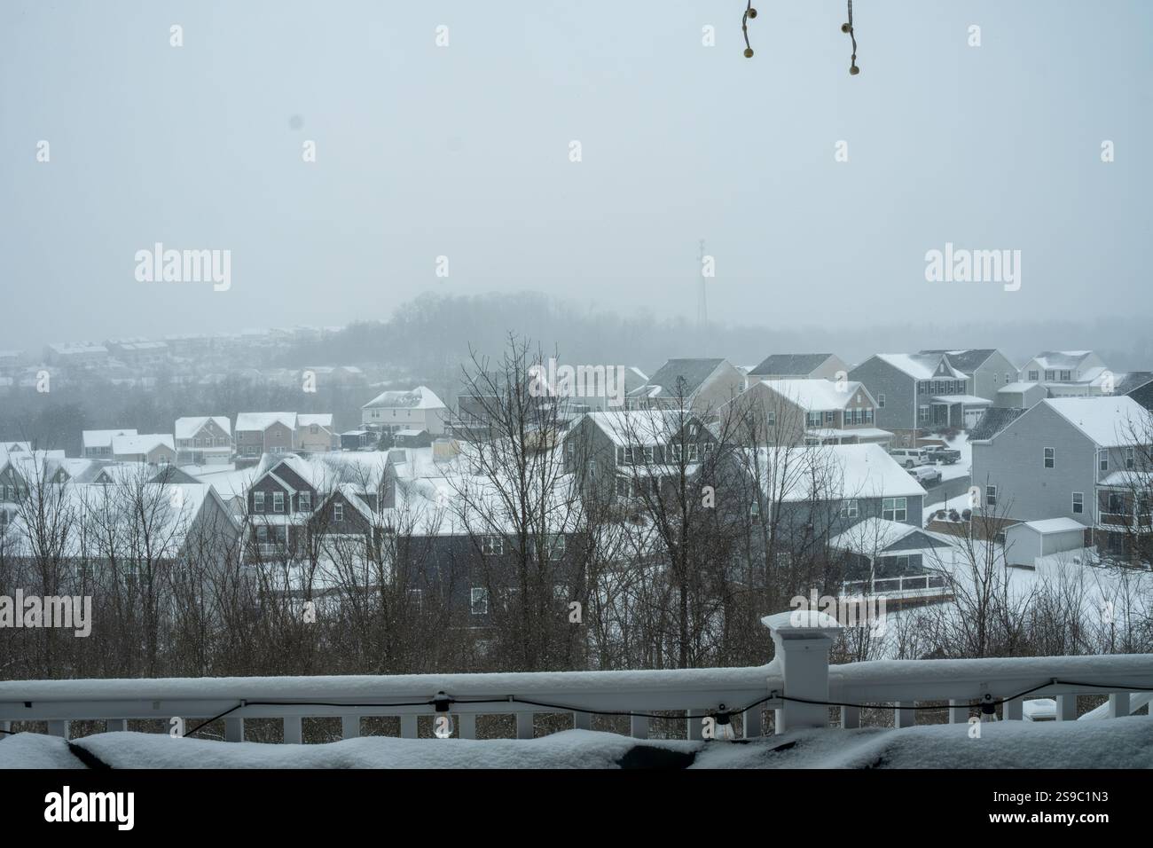 Thick layers of snow cover rooftops and trees in a quiet suburban ...