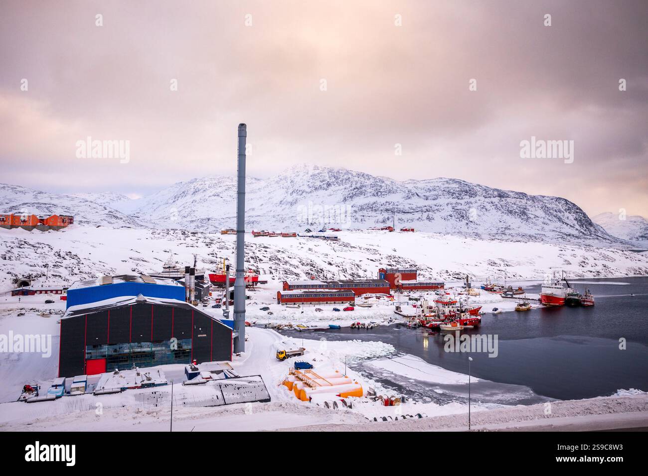 Fishing boats and harbor buildings with mountains in the background ...