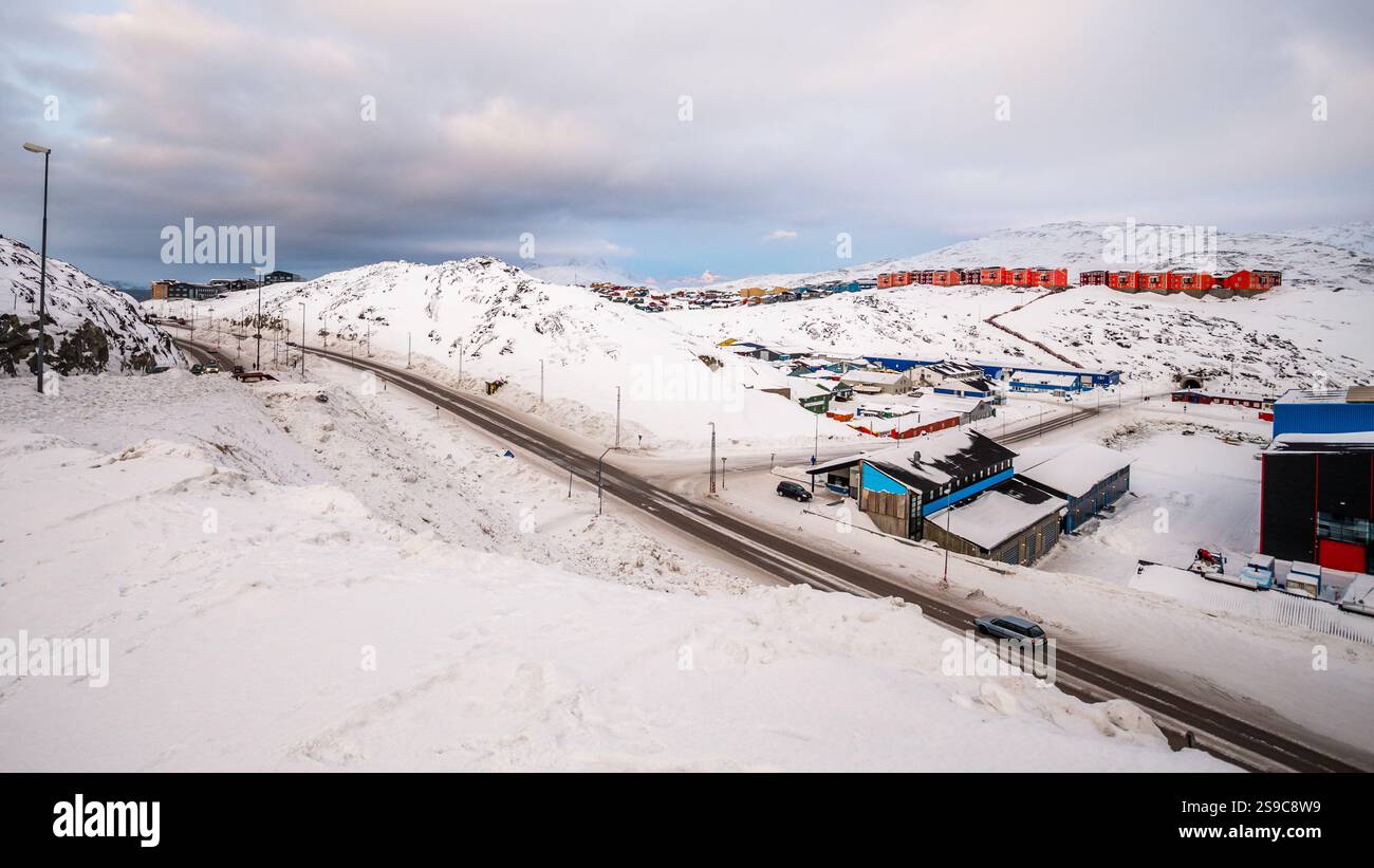 Road between snow hills and Inuit houses in the background, Nuuk city ...