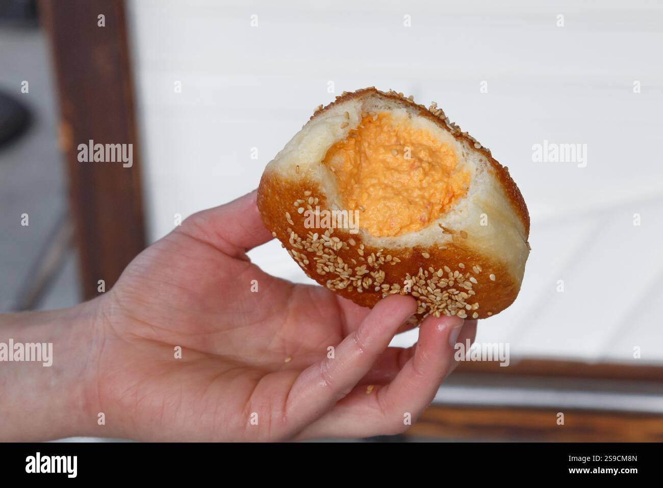 Hand Holding a Cream-Filled Bread Roll with Sesame Seeds Stock Photo ...