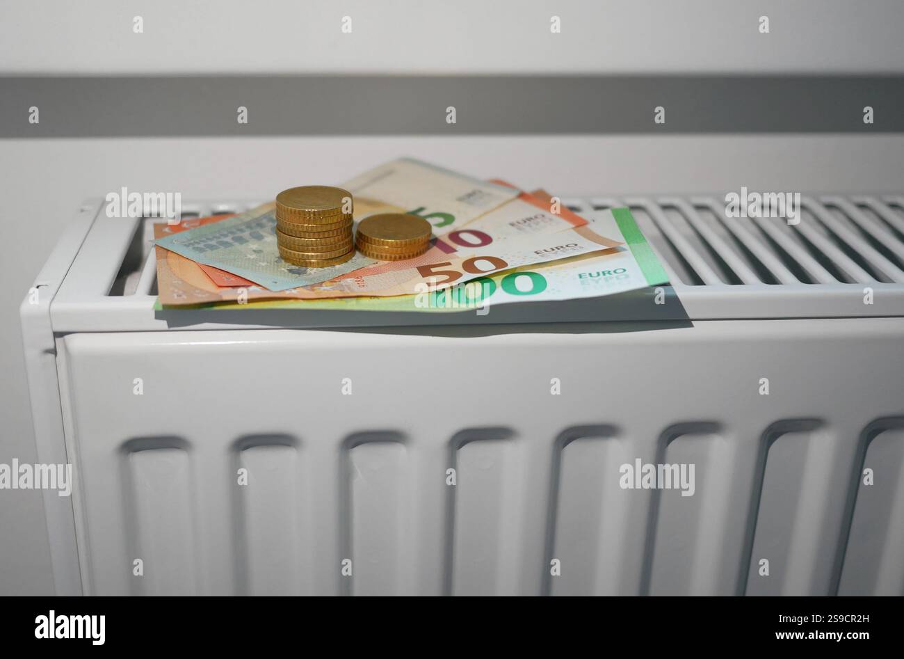 Money on the heating radiator battery. Euro banknotes on a thermostat ...