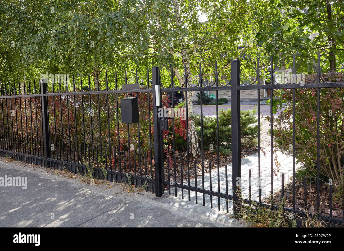 Closed metal fence door. Forged metal fence with hedge vegetation Stock ...