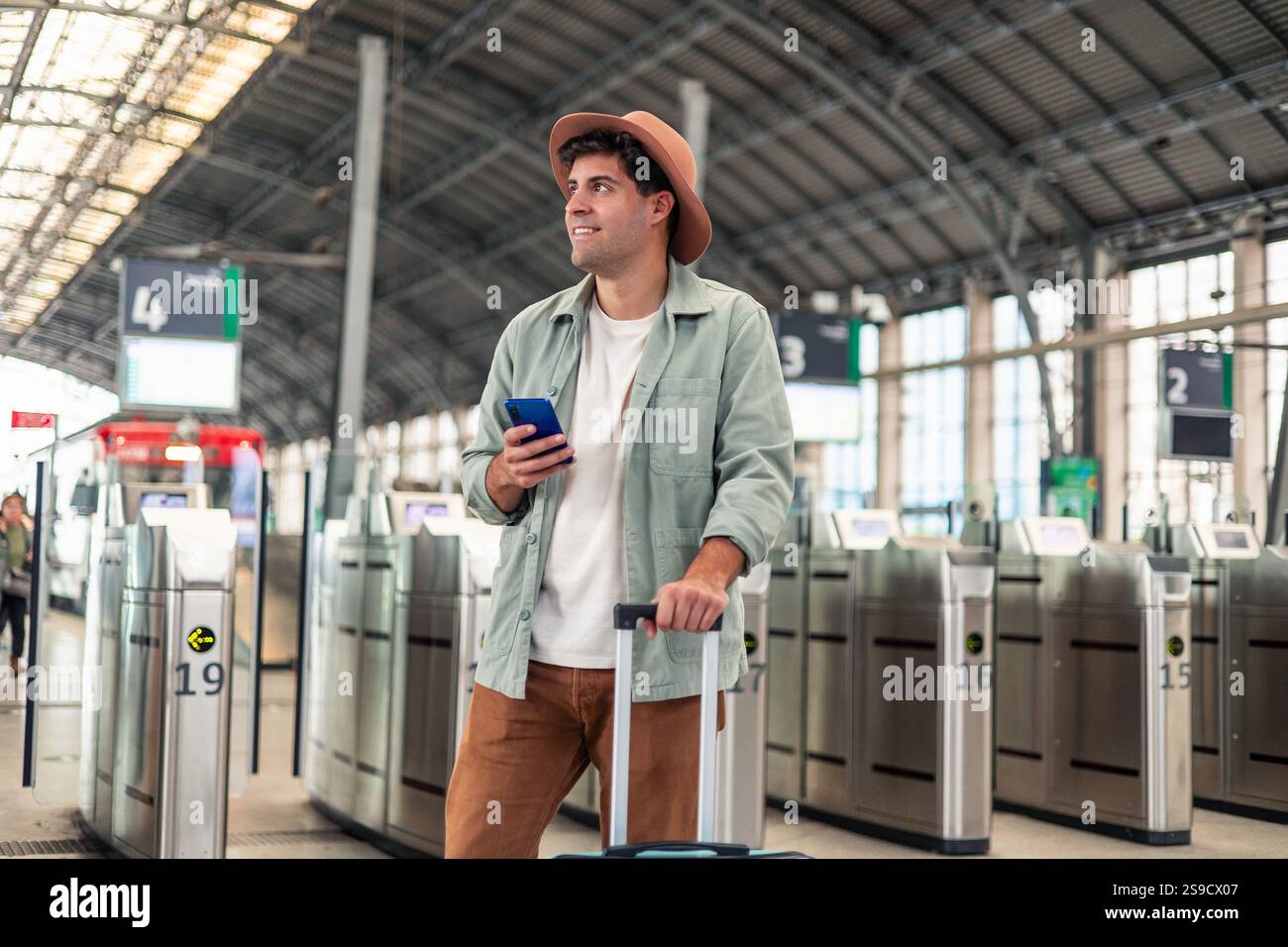 Happy latin male traveler with hat and trolley suitcase holding ...
