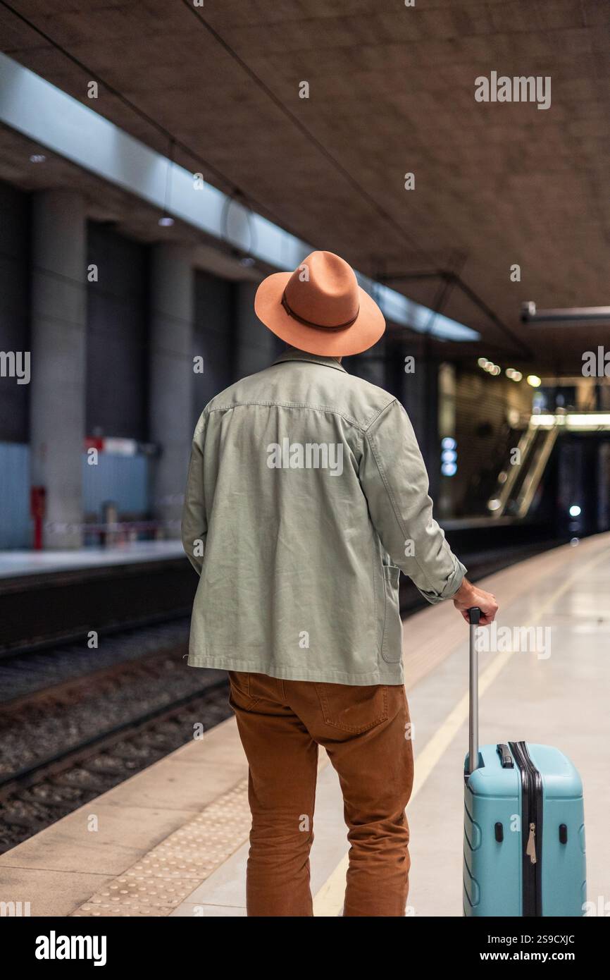 vertical Stylish latin tourist wearing a hat and pulling a light blue ...