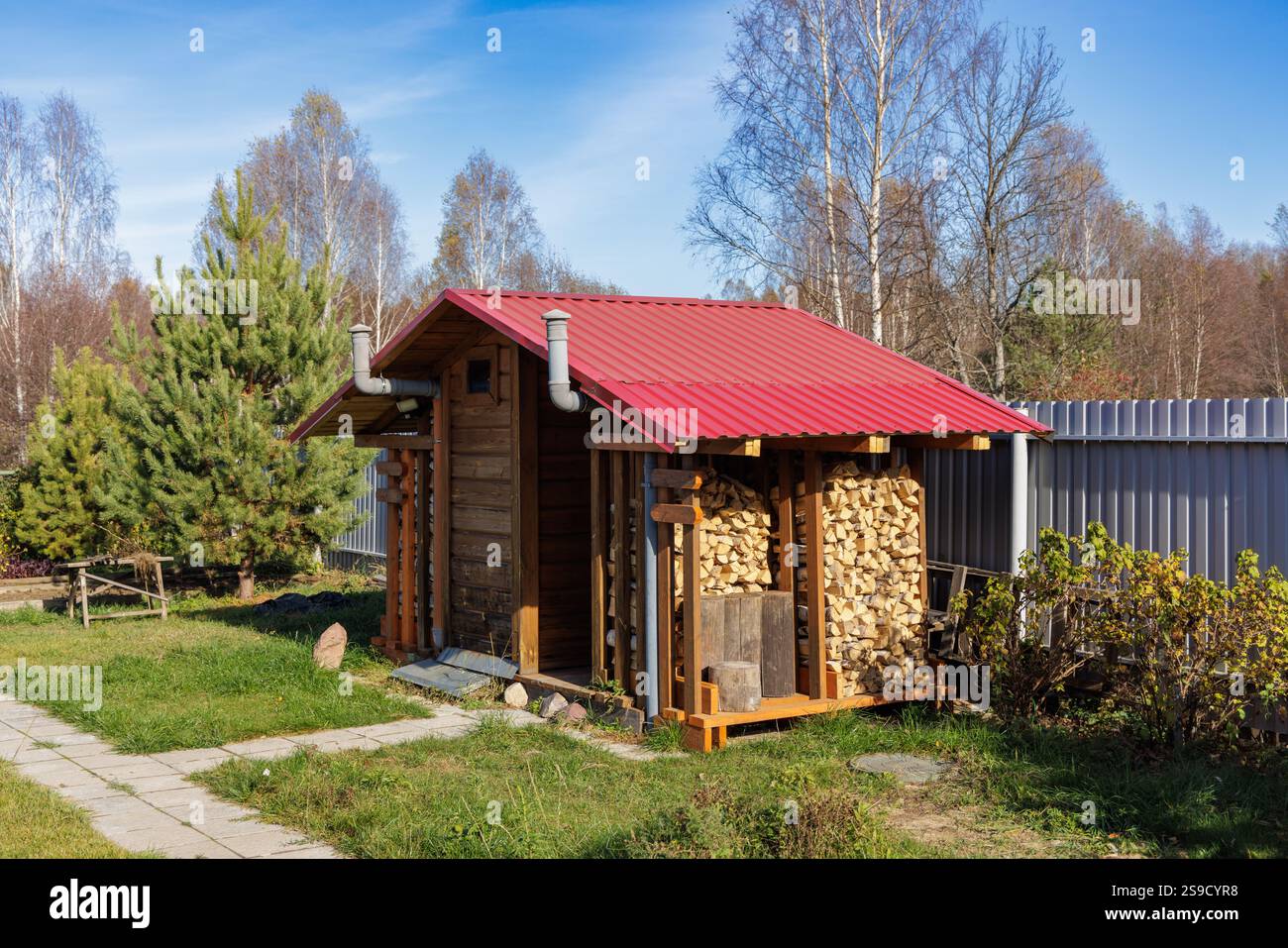 A traditional wooden outhouse with a red roof, located in a rural area ...