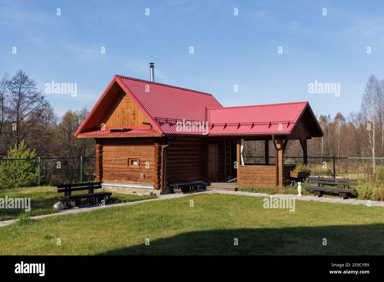 A cozy wooden cabin with a red roof set in vibrant greenery, showcasing ...